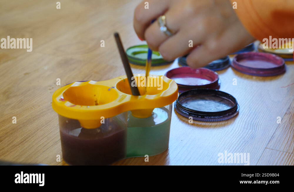 Close-up shot of painting brush being quickly put into cup with water ...