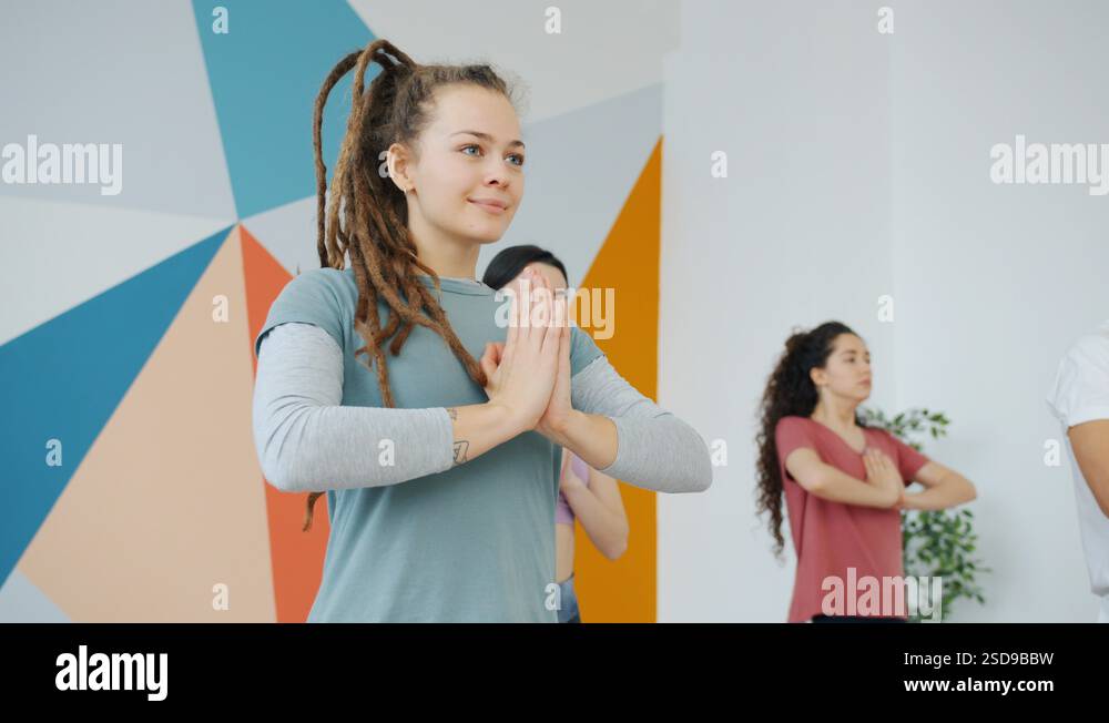Cute girl doing yoga with group of people practising balance asanas ...