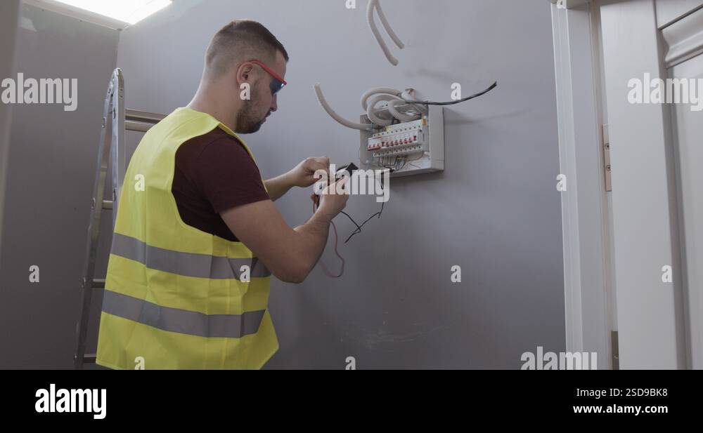 a male electrical engineer checks the connections and voltage in the ...