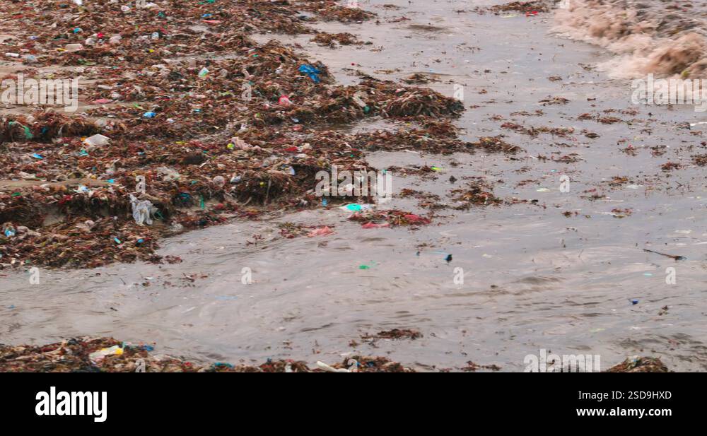 Sea waves full of litter hitting the beach. Huge dump in tropical ...