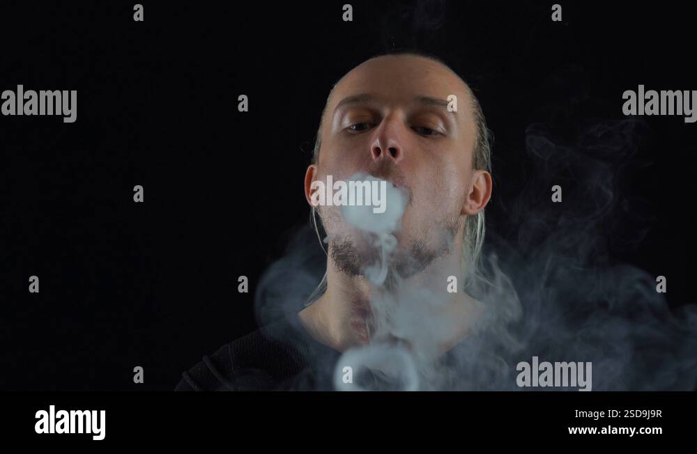 Man vaping big ring of steam and sends it to the camera with in slow ...
