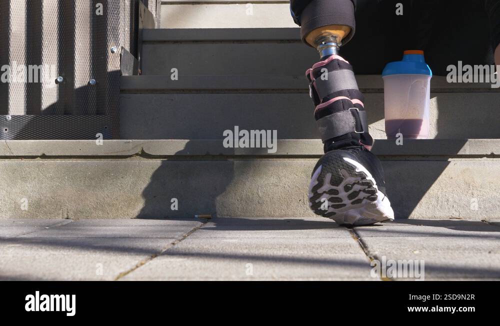 Young woman with leg prosthesis with smoothie sitting on steps Stock ...