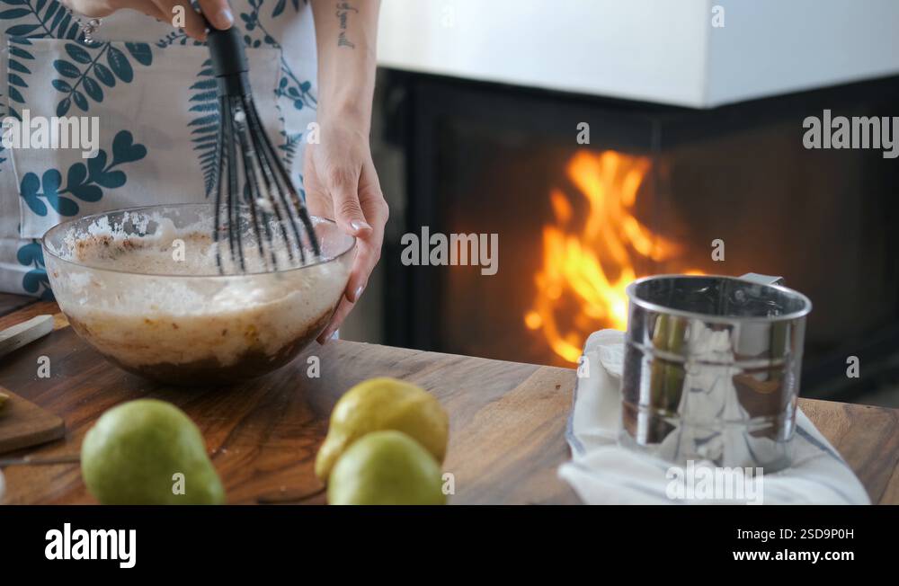 woman stirs the dough with a whisk in a cup standing by a burning ...
