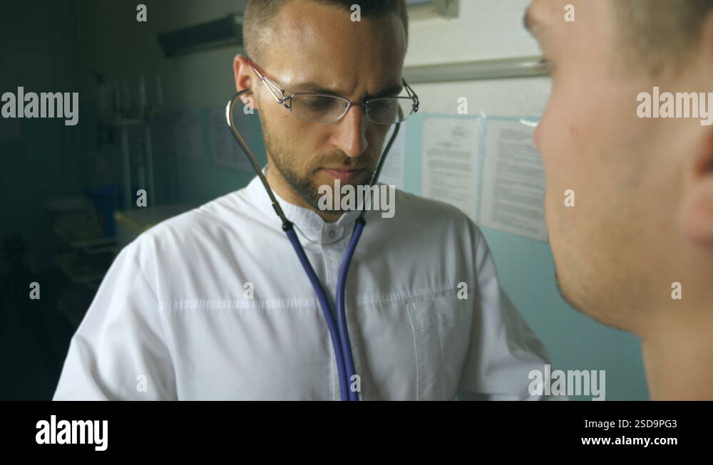 Medic checking chest of guy in her office at the hospital. Doctor ...