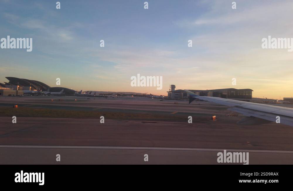 Wing side view of plane taking off from LAX at sunset Stock Video Footage - Alamy
