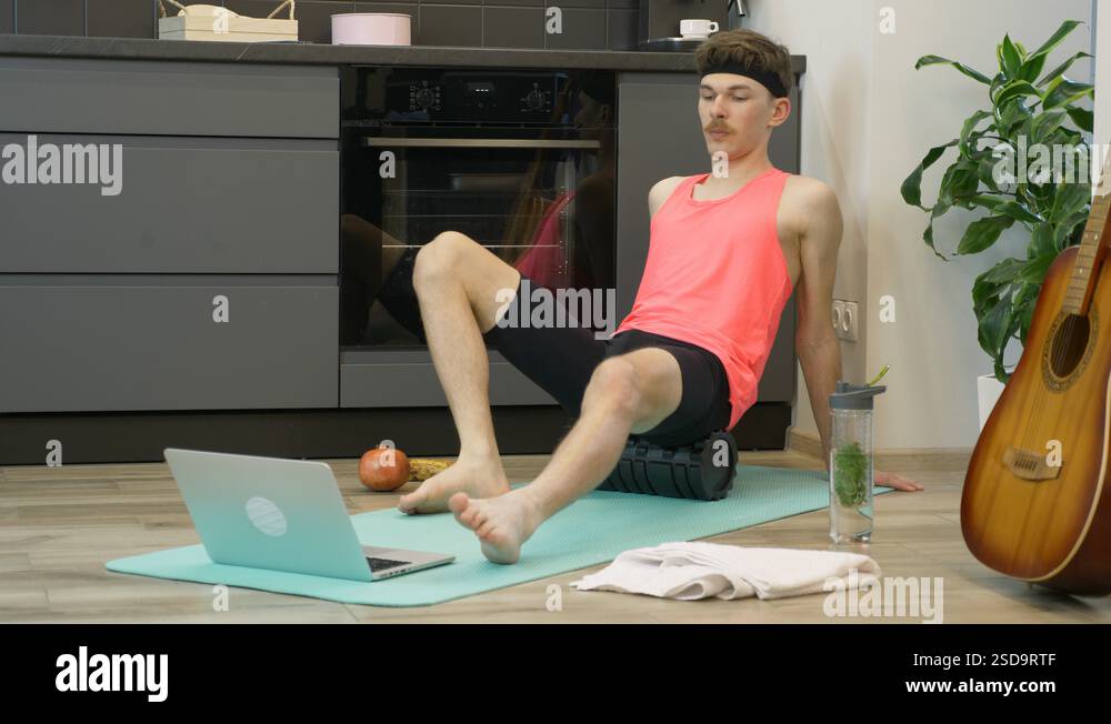 Young fit guy with fitness roll doing rehab exercises using online ...