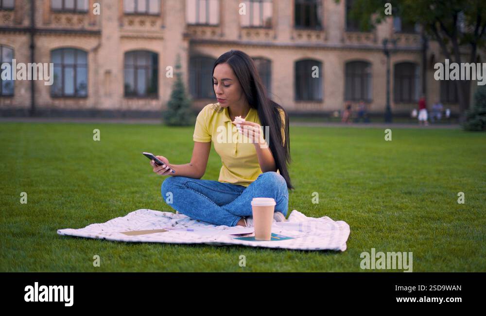 Young girl on a picnic. Girl scrolls the phone and eats a sandwich 4K ...