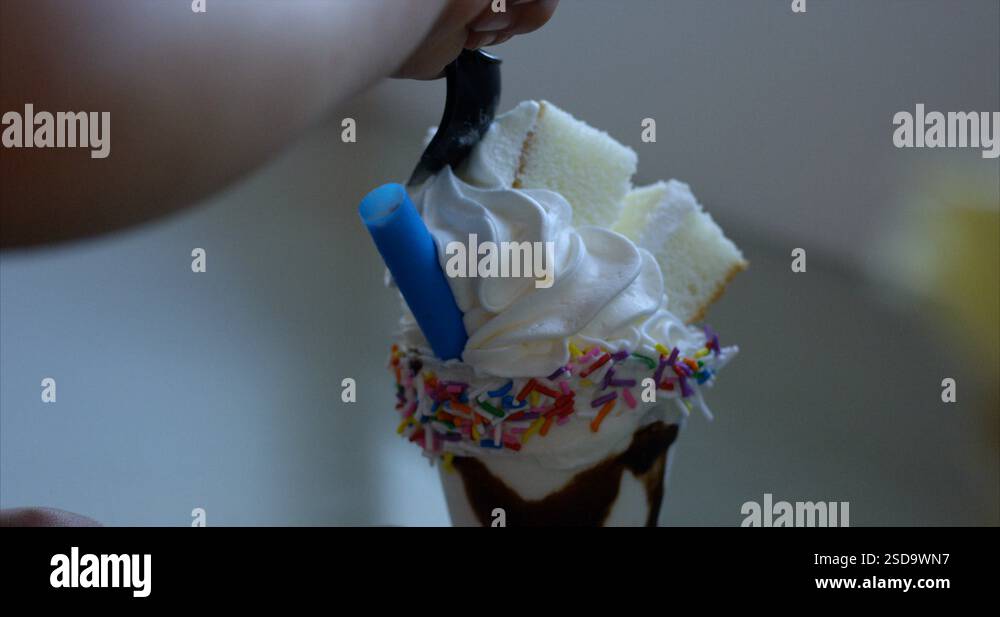 Toddler begins to eat fancy ice cream treat - indoors - close up on ice ...