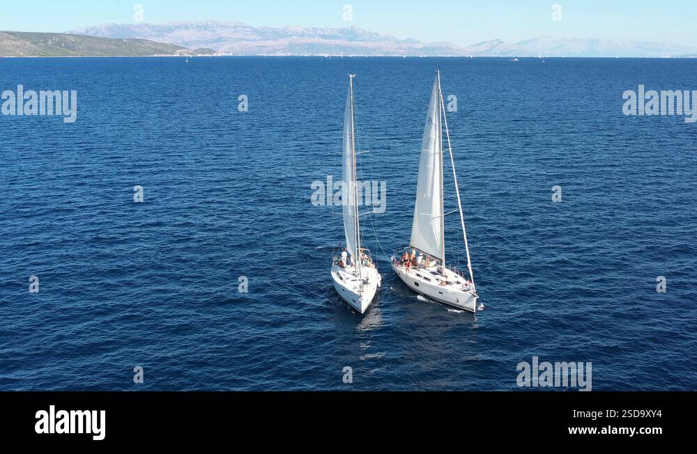 Two sailing yachts closely to each other, youth have fun on yachts ...