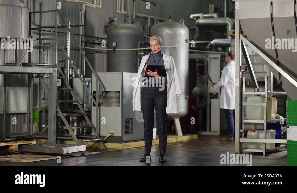 Female quality control expert making notes in report in factory Stock ...