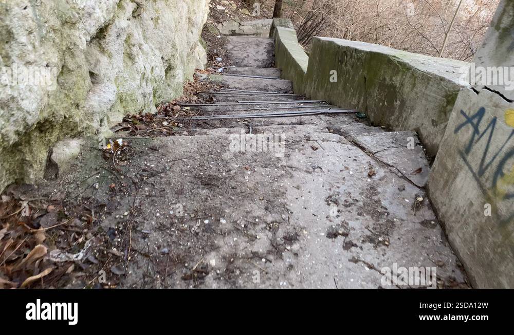 POV walking down stairs, long old ruined and dirty stone staircase on ...