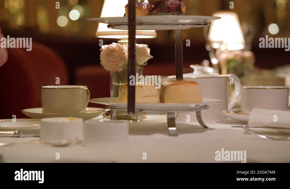 A lady's hand is picking up a piece of scone from the afternoon tea ...