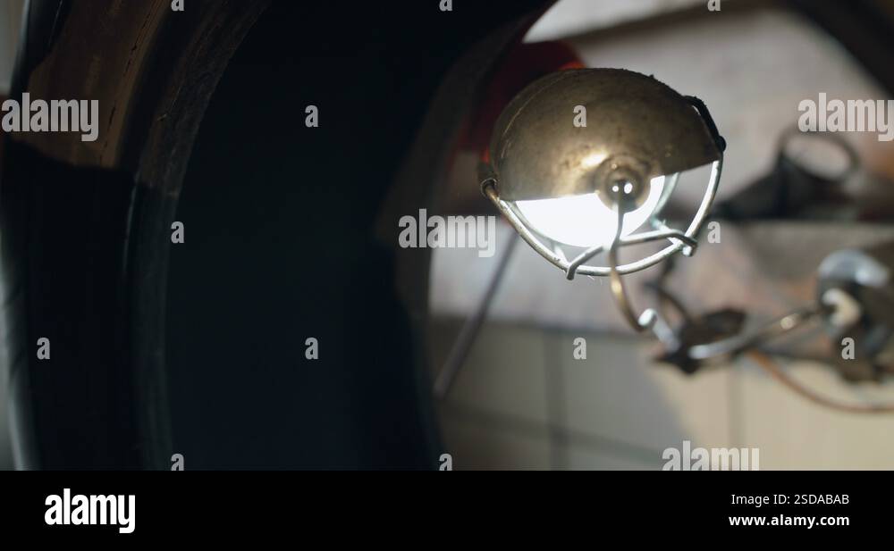 Mechanic holds a lamp and preparing a tire for repairing on auto ...