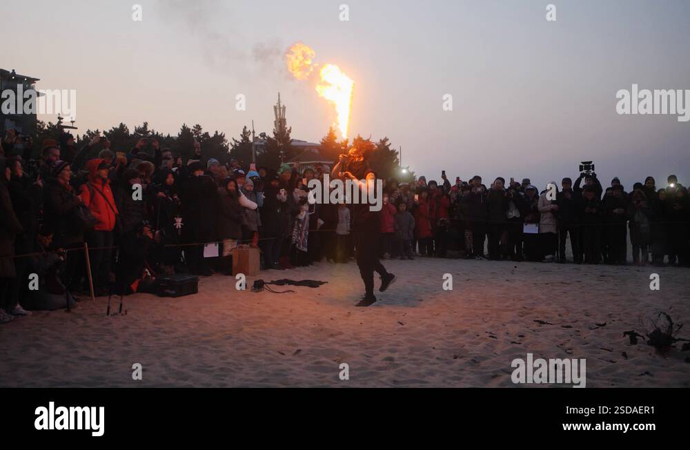 Slow clip of a male masked stunt performer dance with fire in front of ...