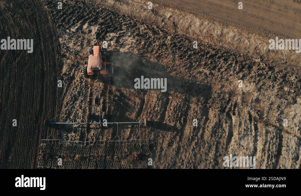 Aerial top view farm tractor with rotary harrow plow preparing land for ...