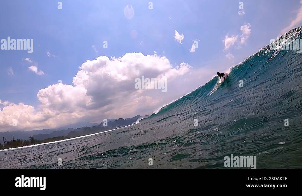 Super slow motion of a surfer catching a big waves and then is seen ...