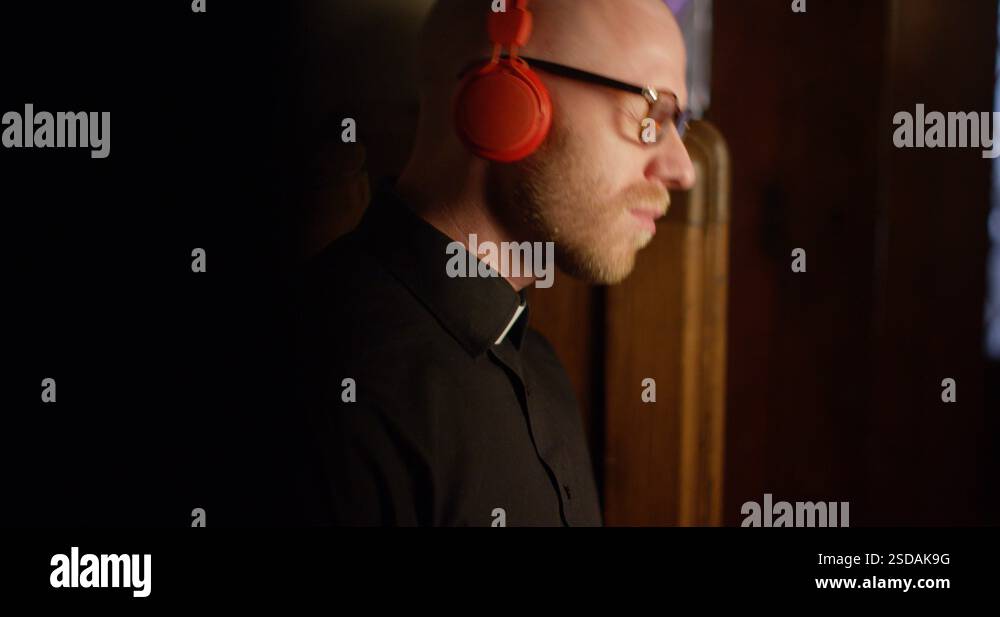 4k a young priest listening to his favourite head banging music track ...