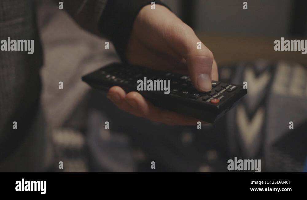 A Man's Thumb Finger Pressing On The Buttons Of A TV Remote Control ...