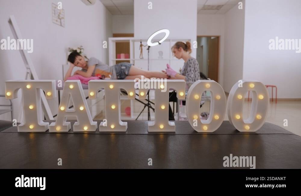 A word- tattoo in a tattoo parlor, in the background a tattoo master ...