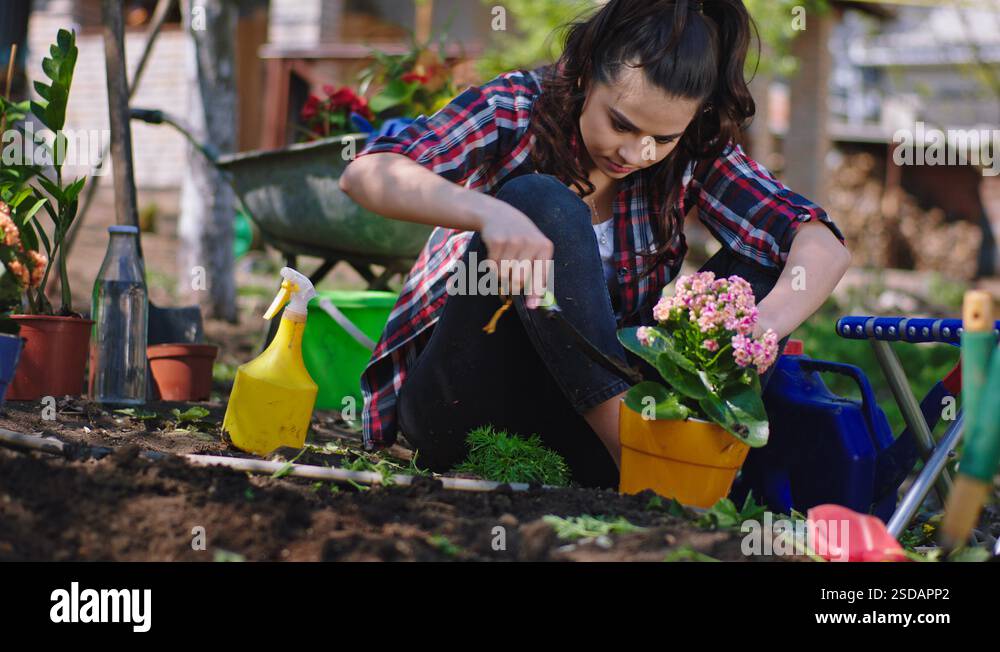 Charismatic concentrated lady take care after the flowers from the pots ...
