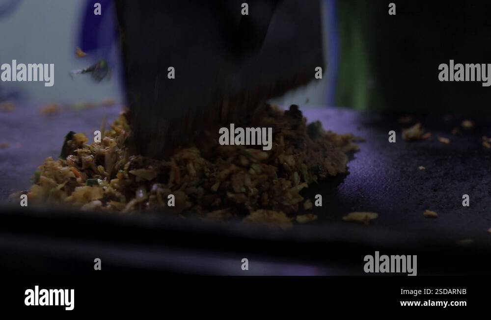 Close-up of a man chopping cooked Kottu Roti, a traditional Sri Lankan ...