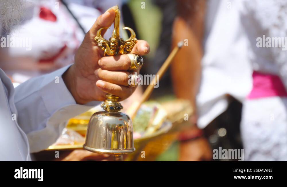 Religious ritual in Bali, hindu ceremony, close-up of hands ringing a ...