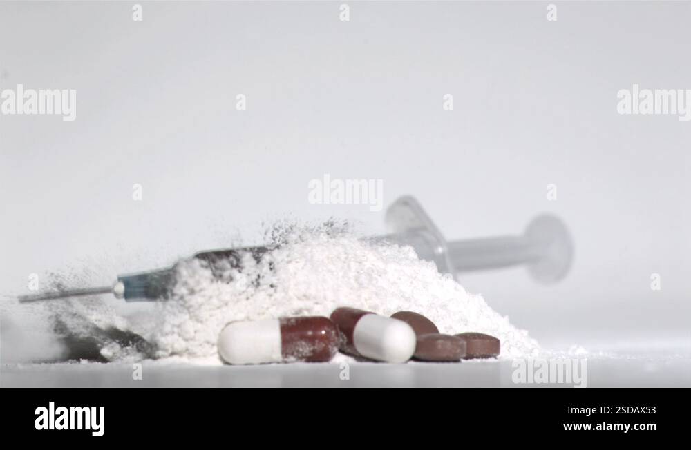 Syringe falling on white drug with pills Stock Video Footage - Alamy