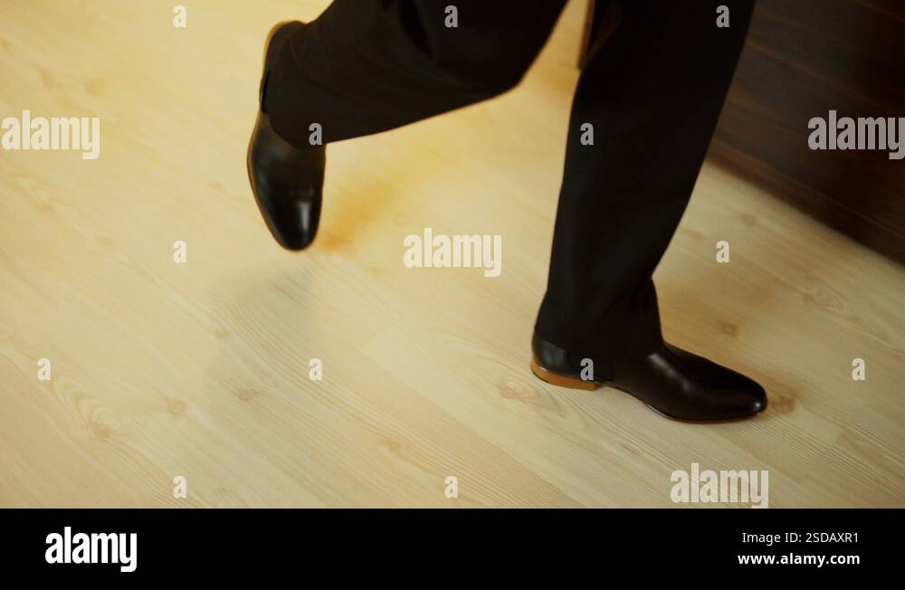 Black clean stylish shoes and black trousers go on wooden floor in ...