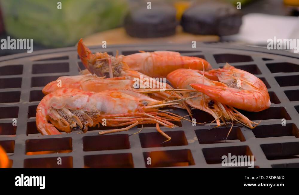 Close up: chef grilling red king prawns on brazier with hot flame ...