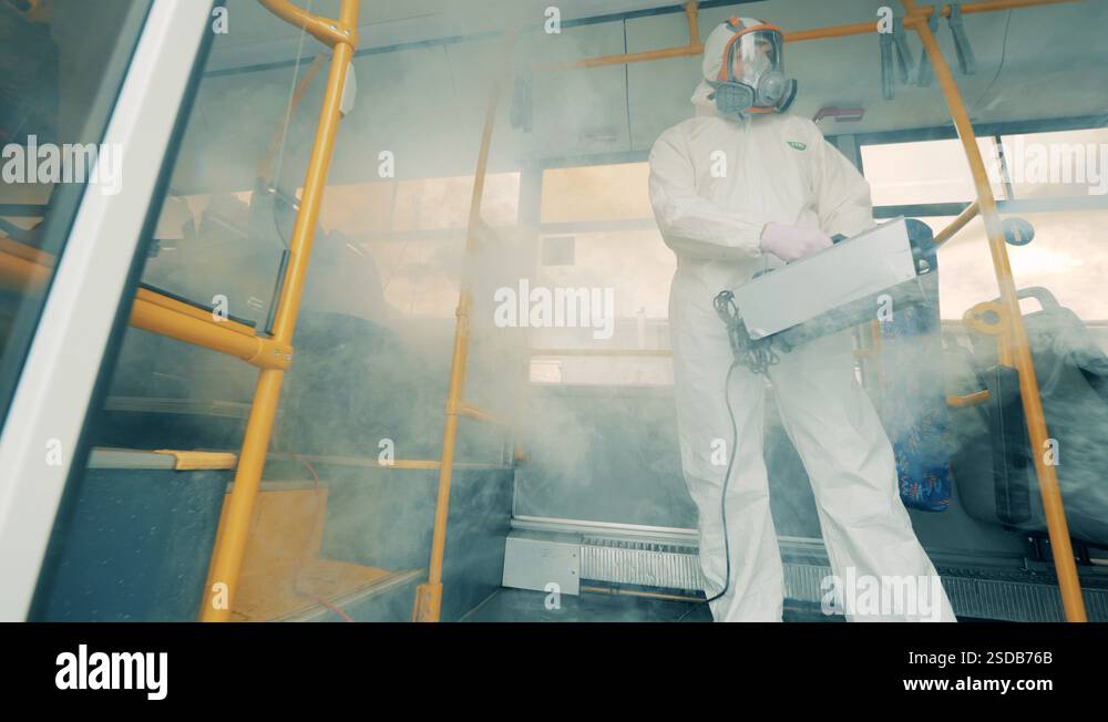 Fumigation of a bus interior done by a specialist in a hazmat suit ...