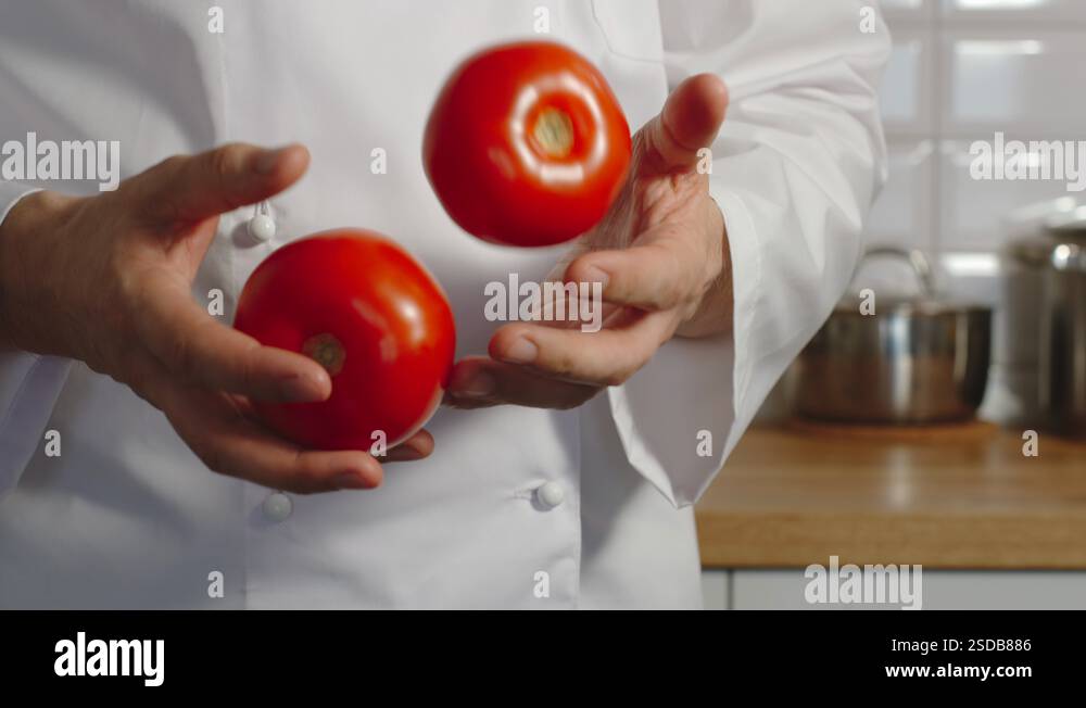 CLOSE UP: Male Cooker juggles a red tomatoes in a kitchen - Slow motion ...