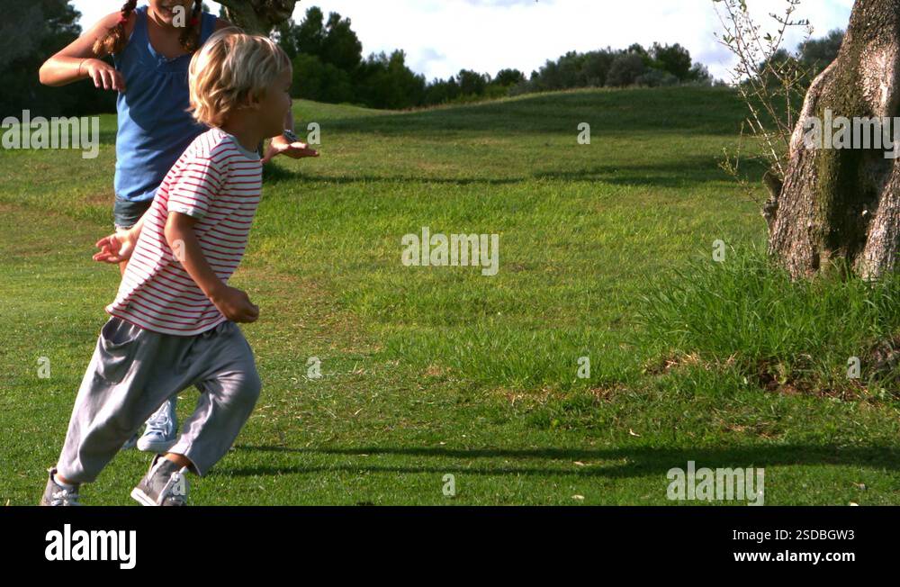Girl child running around after a large tree Stock Video Footage - Alamy