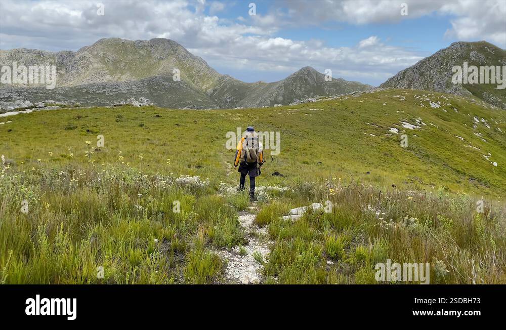 Mountain hiker with heavy backpack walks alone in slow motion through ...