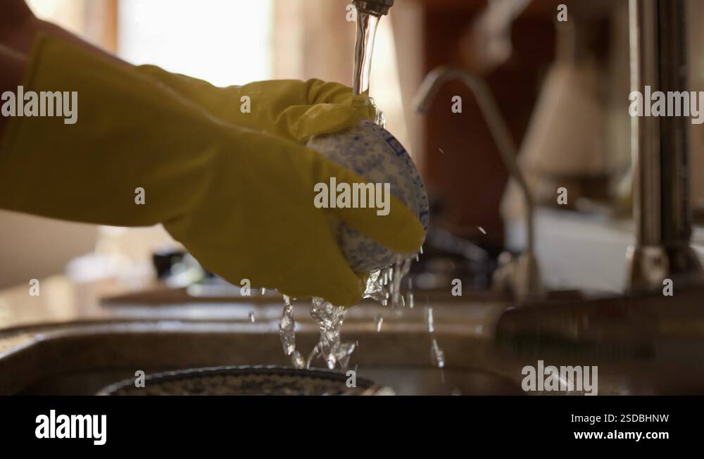 Cleaning in the kitchen. Closeup of female hands wash a plate in the ...