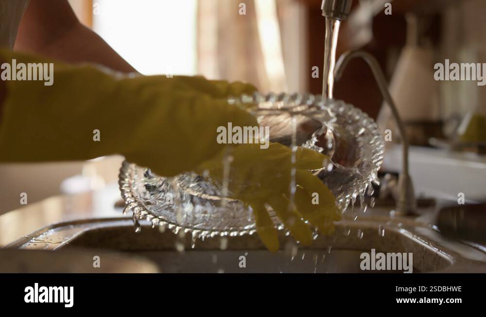 Closeup of female hands wash a plate in the kitchen sink. Macro frame ...