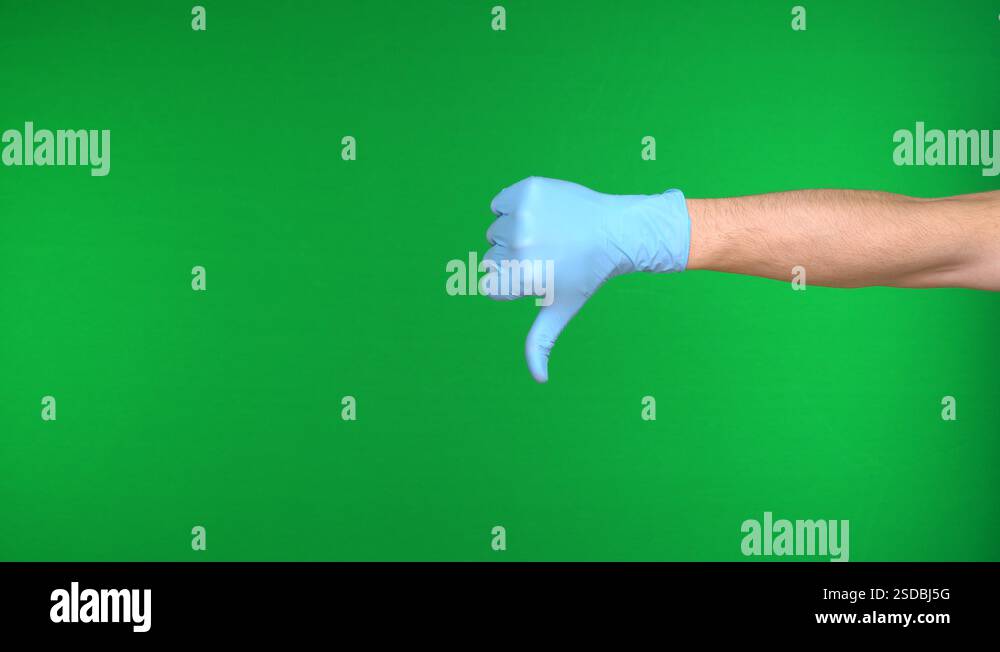 Men's hand in medical glove shows thumb down, dislike sign. Green ...