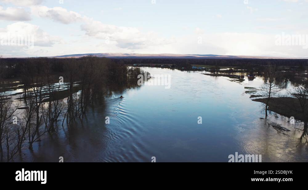 Three people on old powerboat floating on floodplain river / Evacuation ...