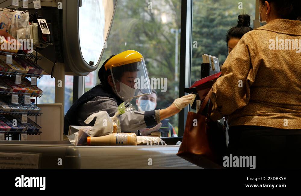 Woman cashier wear face mask and glass shield in ATB supermarket due to ...