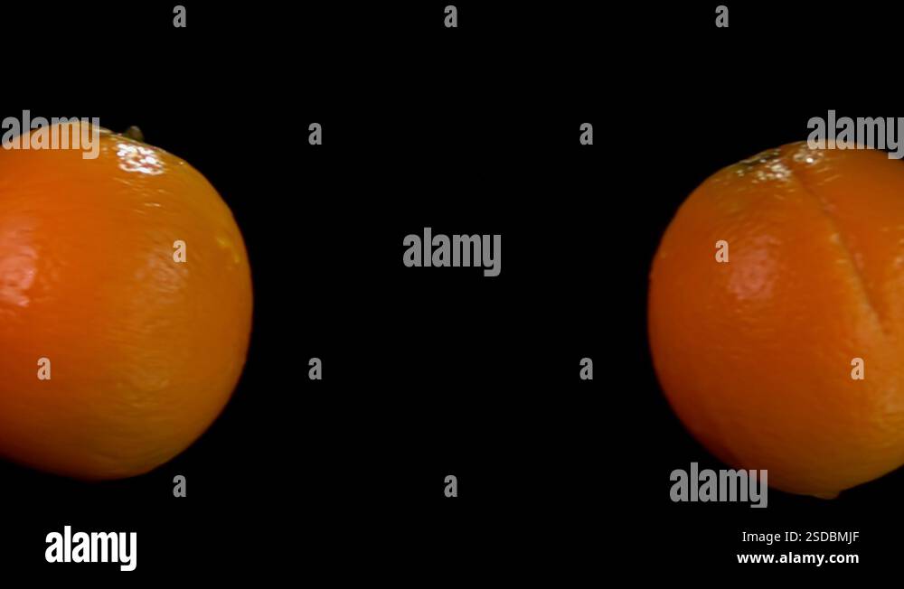 Two juicy oranges are flying and colliding with each other rising drops ...
