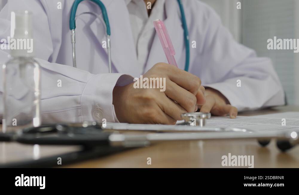 The hand of a female doctor is writing information on the paper Stock ...