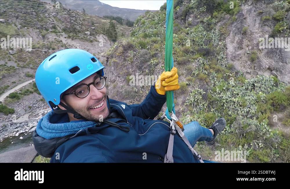 Young man smiles as he goes down a zip line in Peru. Young boy rides ...