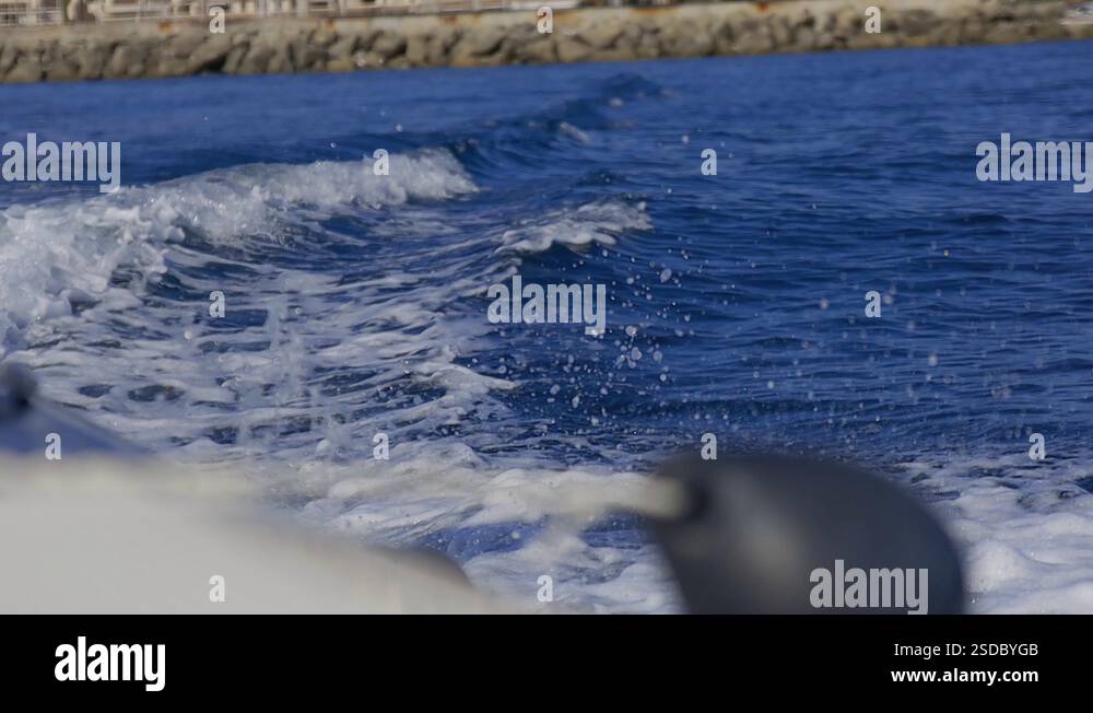 sideways view of a boat looking at the blue sea water splashing on the ...