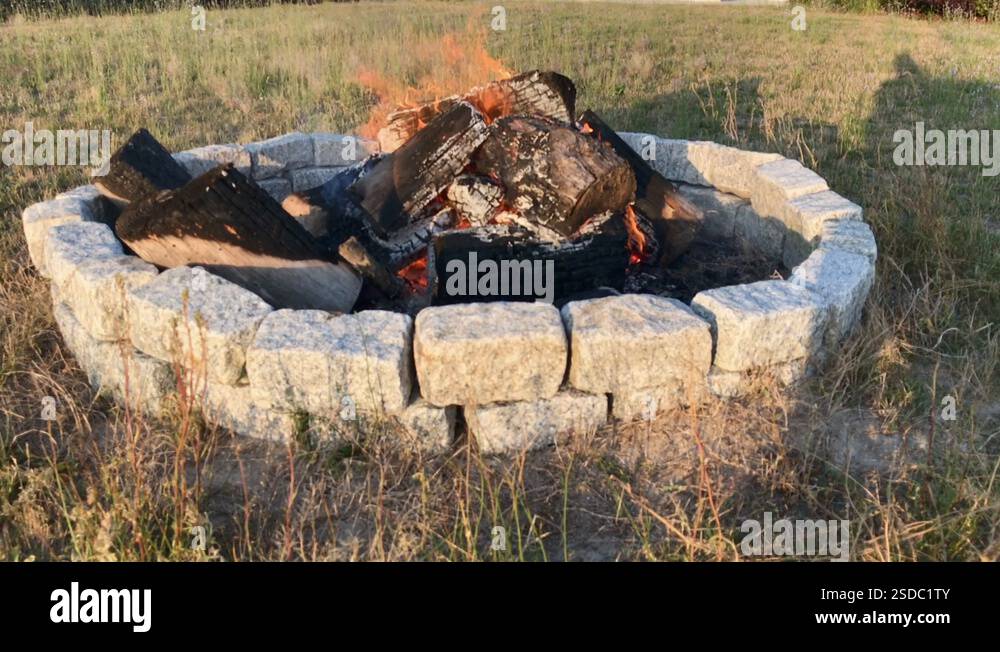 Wood log fire burning in custom made granite fire pit in backyard on ...