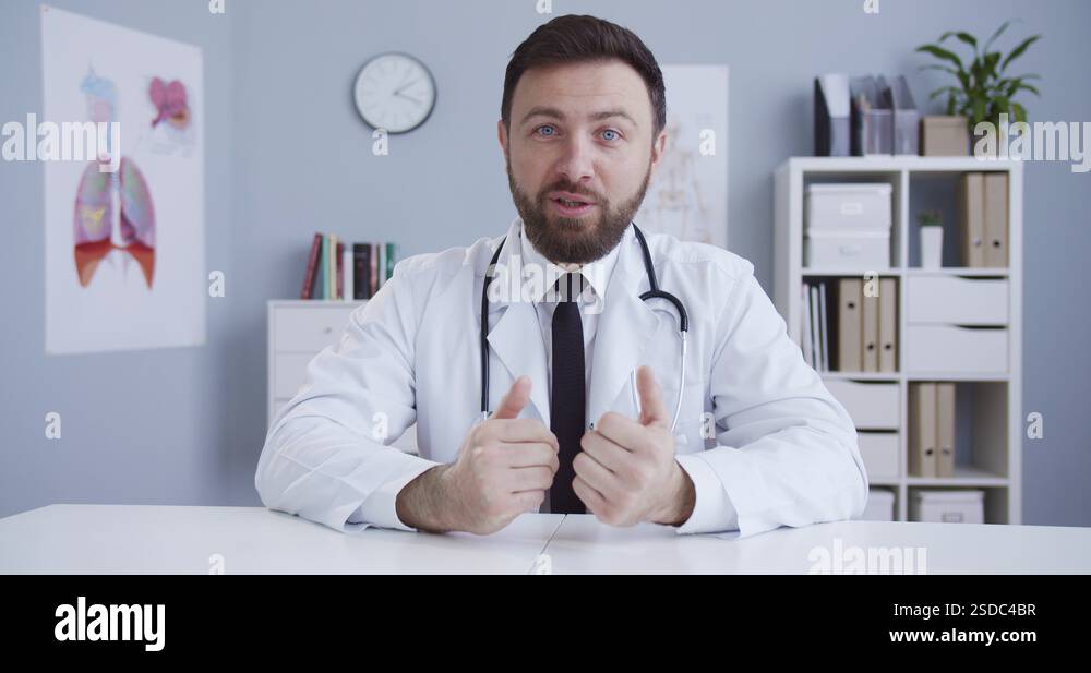 Handsome blue eyed male doctor blogger in white robe in clinic office ...