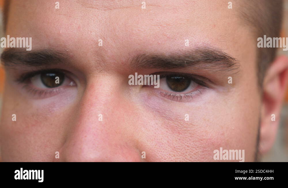 Close up brown eyes of guy staring and blinking with a disappointment ...