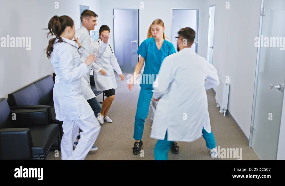 Group of young and mature doctors and nurses dancing excited in front ...