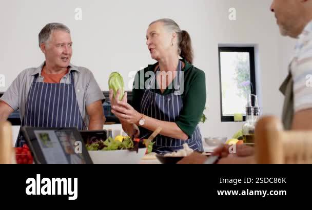 Preparing fresh salad, senior friends enjoying cooking together in ...