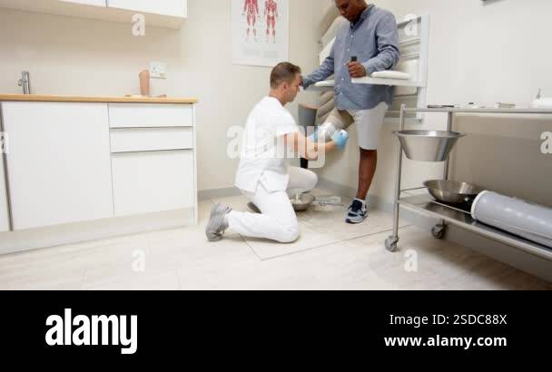 Fitting prosthetic leg, technician assisting patient in medical lab ...