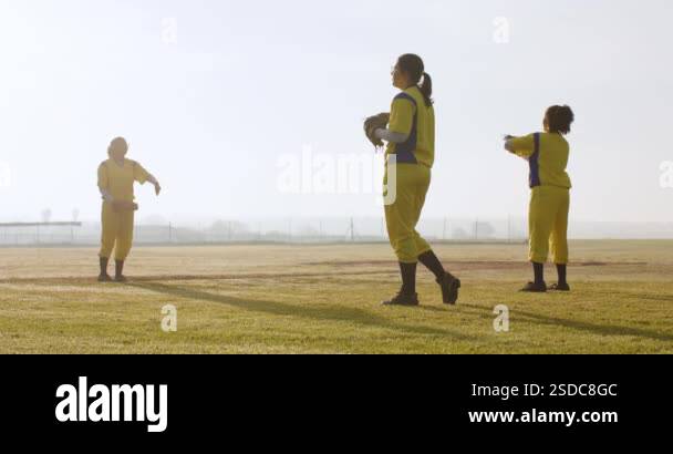 Multiracial female baseball players catching and throwing the ball to ...
