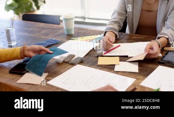 Interior design project, multiracial team discussing sketches and fabric samples together, at ...